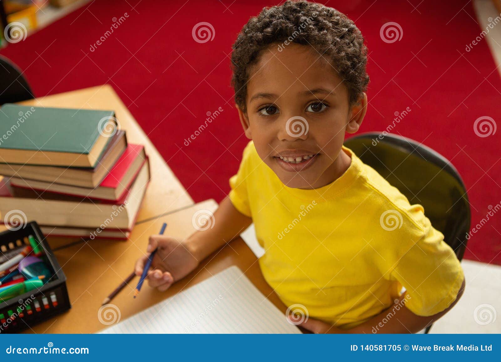 Schoolboy Looking at Camera while Studying at Desk in a Classroom Stock ...