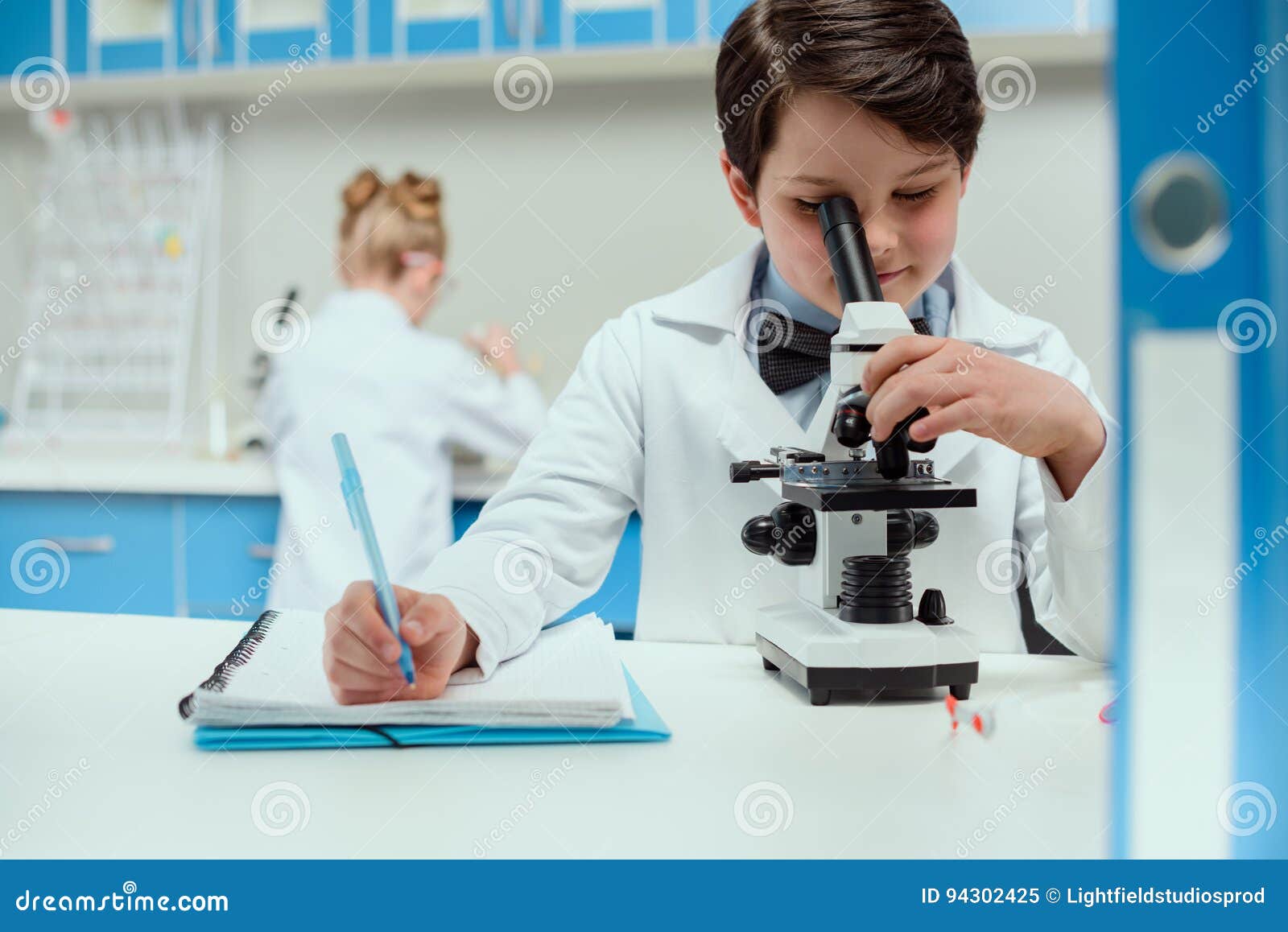 Schoolboy with Microscope and Copybook in Science Laboratory Stock ...