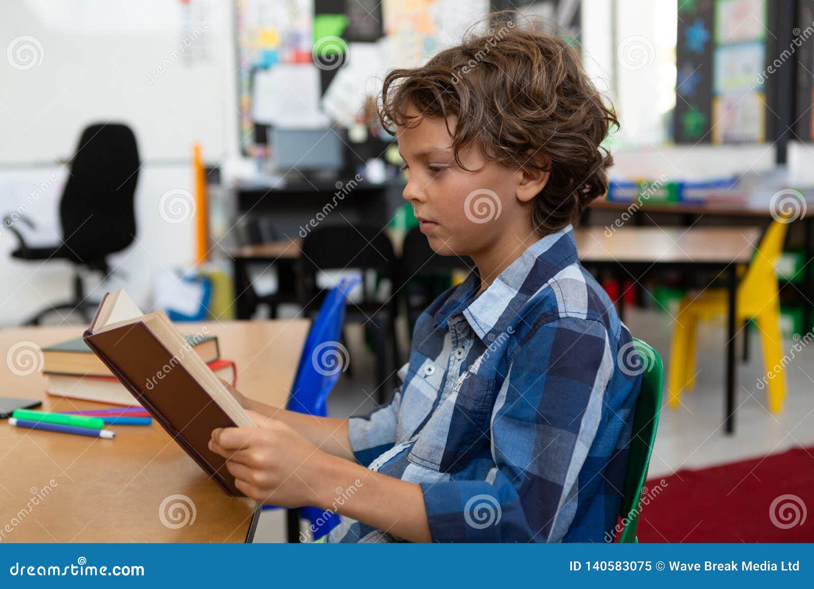 Schoolboy Reading a Book in the Classroom Stock Image - Image of boys ...