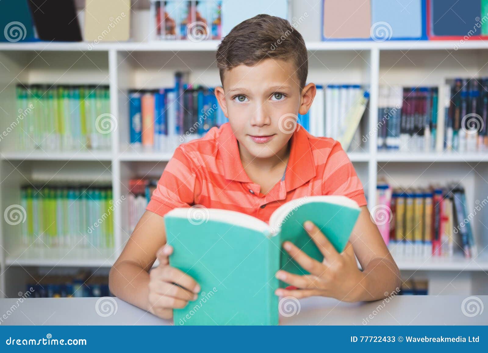 Schoolboy Sitting on Table and Reading Book in Library Stock Image ...