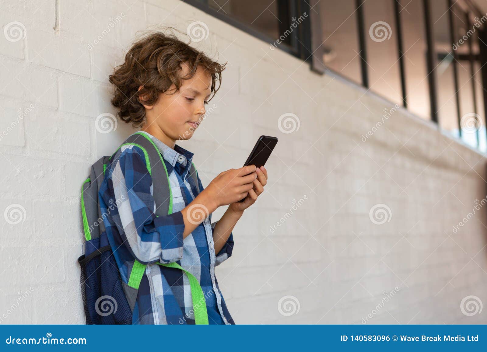Schoolboy Using Mobile Phone in the Corridor Stock Photo - Image of ...