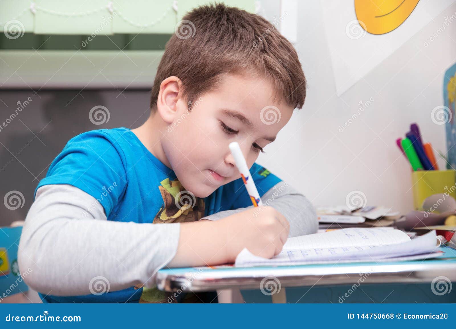 Schoolboy is Using Pen To Practice Writing on a Notebook at His Desk at ...