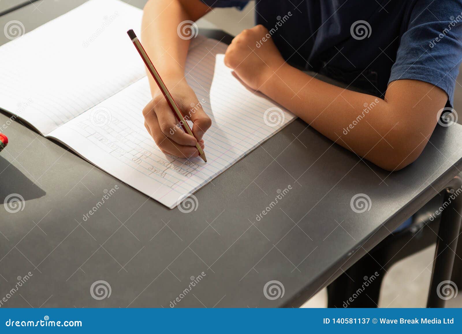 Schoolboy Writing in a Notebook at Desk in Classroom Stock Image ...