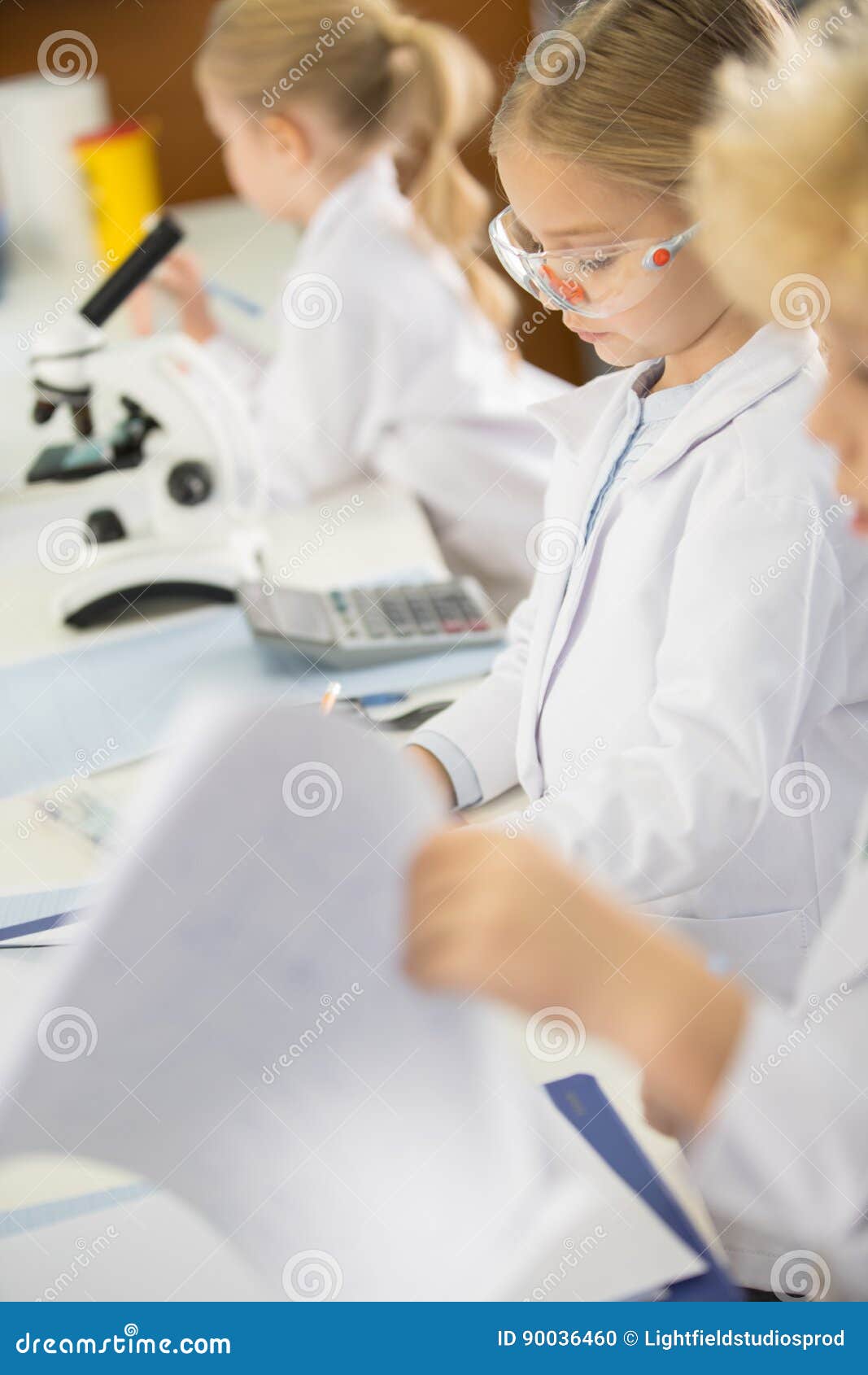 Schoolchildren in White Lab Coats Studying Together and Making Notes ...