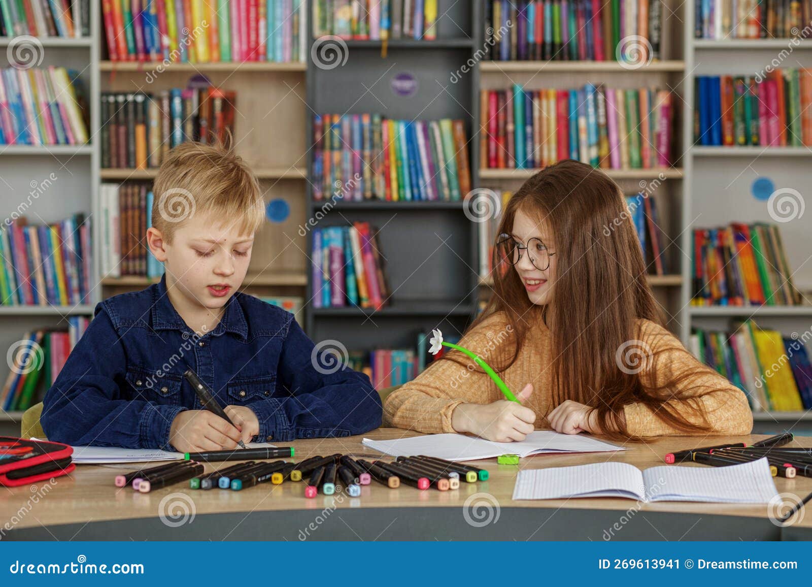 Two Schoolchildren Write and Draw Sitting at Table in Library ...