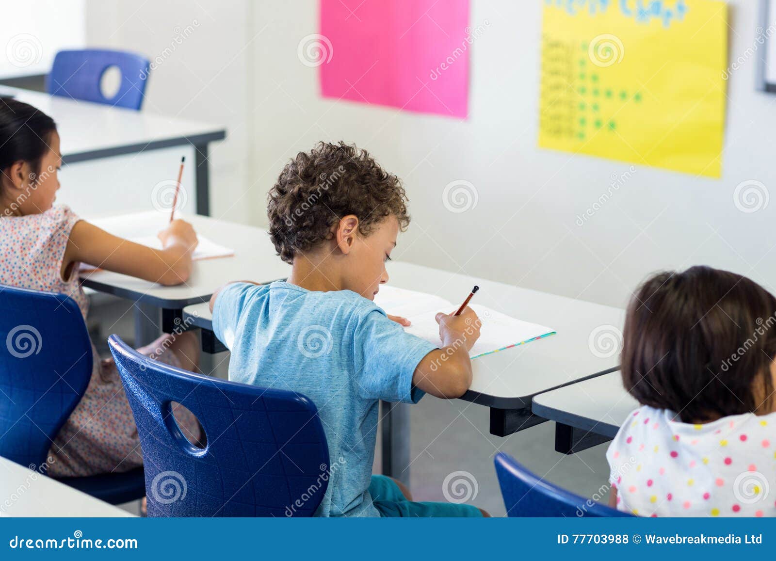 Schoolchildren Writing on Book in Classroom Stock Photo - Image of ...