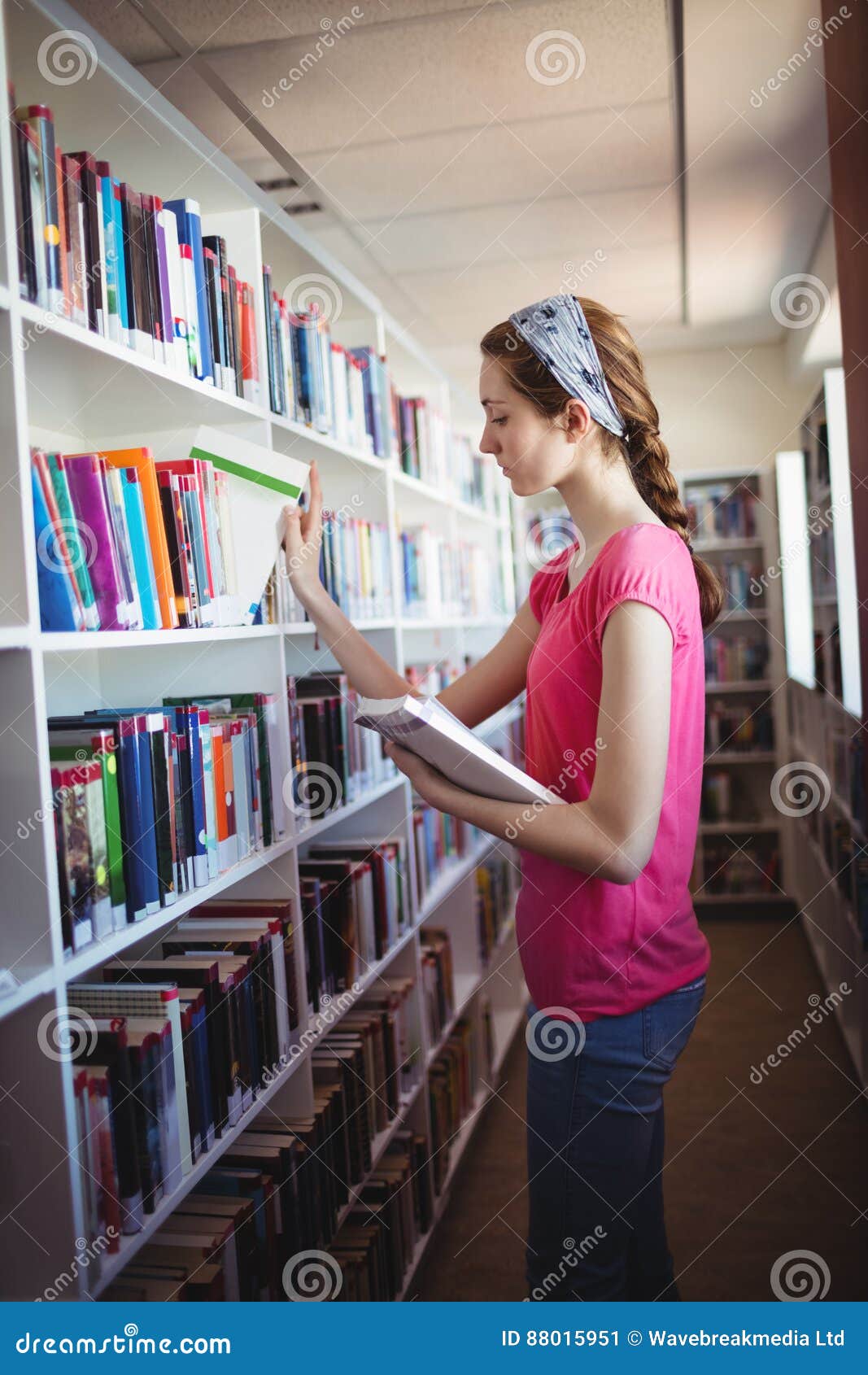 Schoolgirl Selecting Book from Book Shelf in Library Stock Image ...