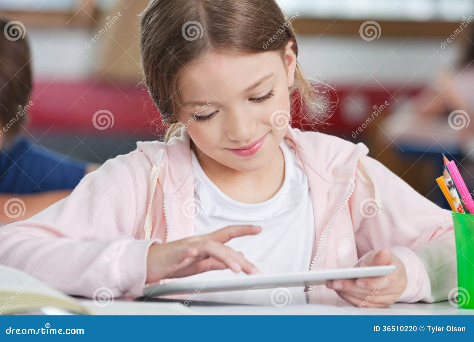 Schoolgirl Smiling while Using Tablet at Desk Stock Photo - Image of ...