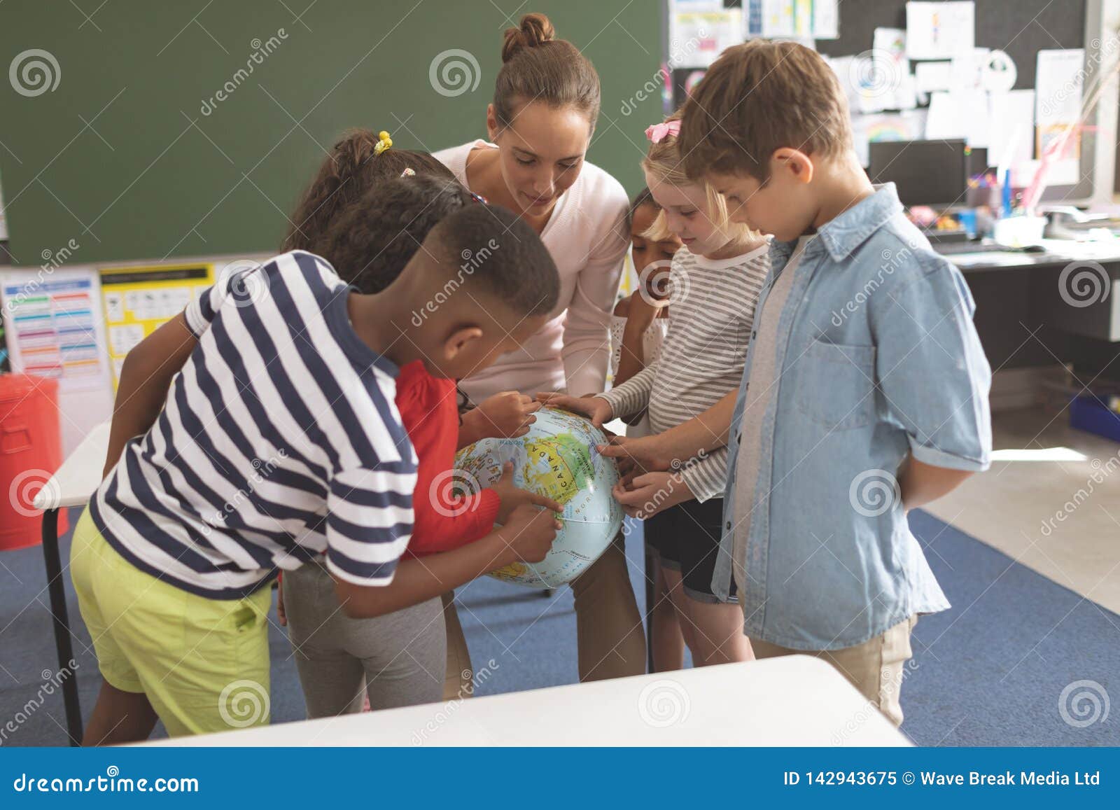 Schoolteacher Explaining Lesson To Students. Clever Kids Learning At ...