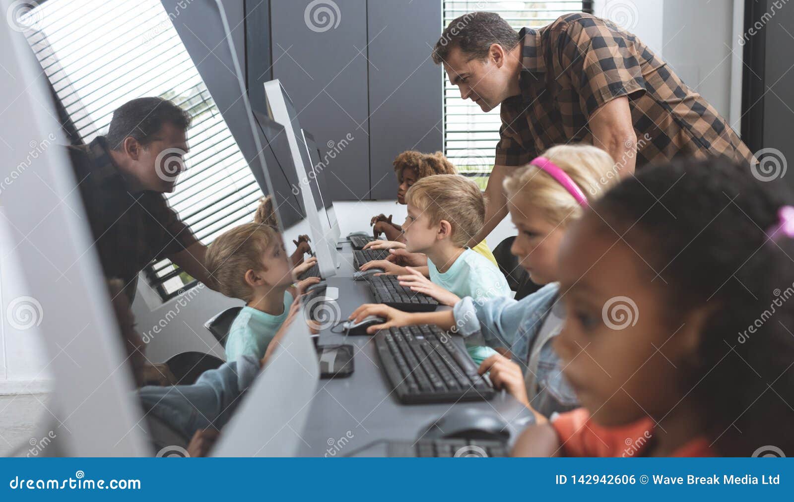 Schoolteacher Teaching To School Kids How To Use Computer Stock Photo ...