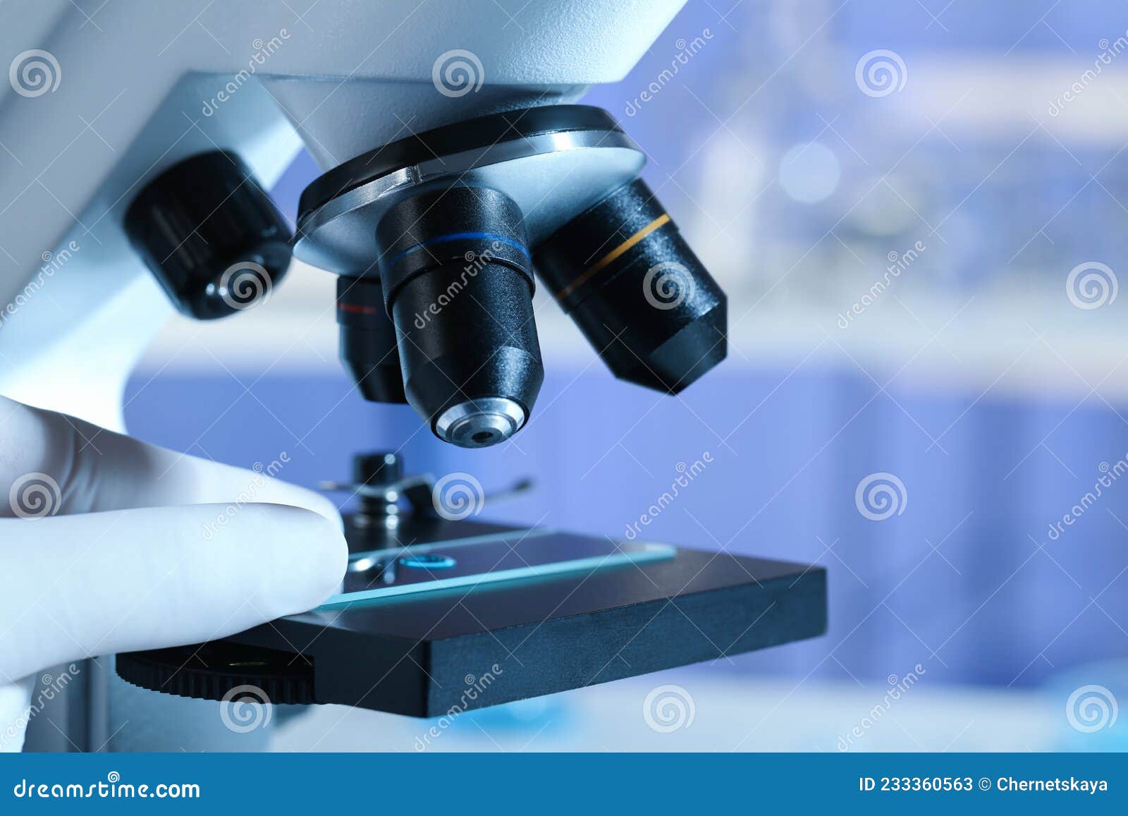 Scientist Examining Sample of Light Blue Liquid on Slide Under ...