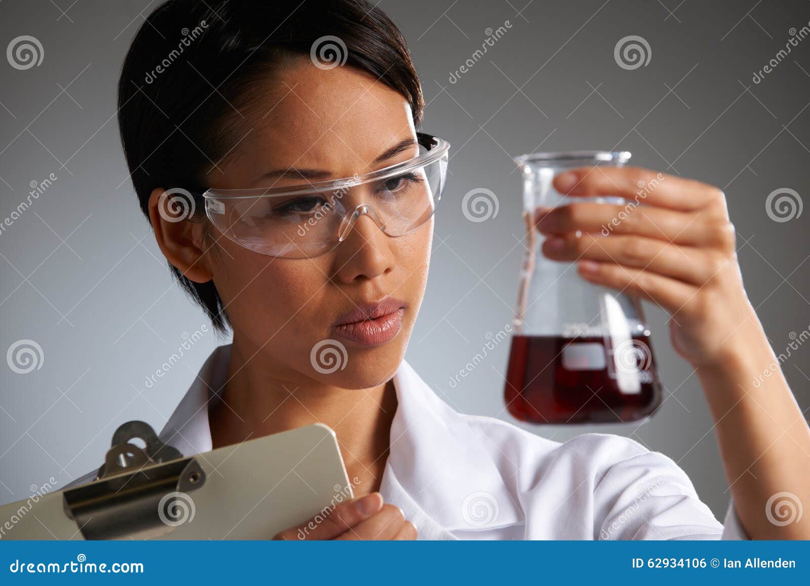 Scientist Holding Clipboard and Examining Beaker Stock Photo - Image of ...