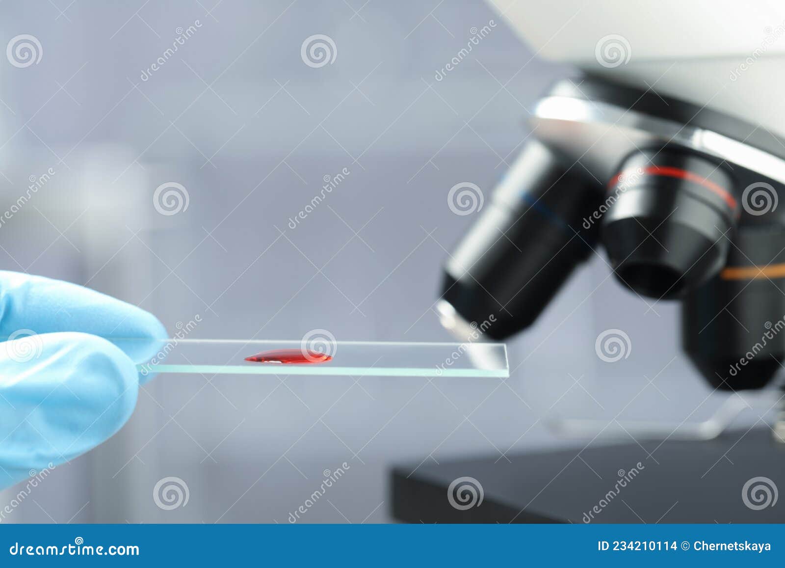 Scientist Holding Microscope Slide with Sample of Red Liquid in ...