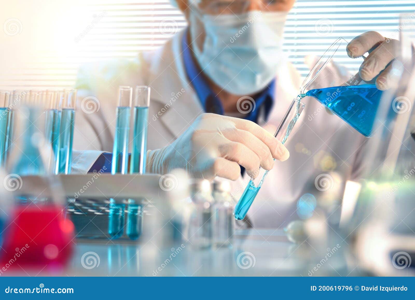 Scientist in Laboratory Pouring Blue Liquid from a Beaker into a Test ...