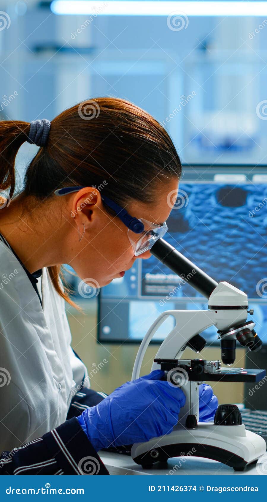 Scientist Looking at Biological Samples Under Microscope Typing on Pc ...