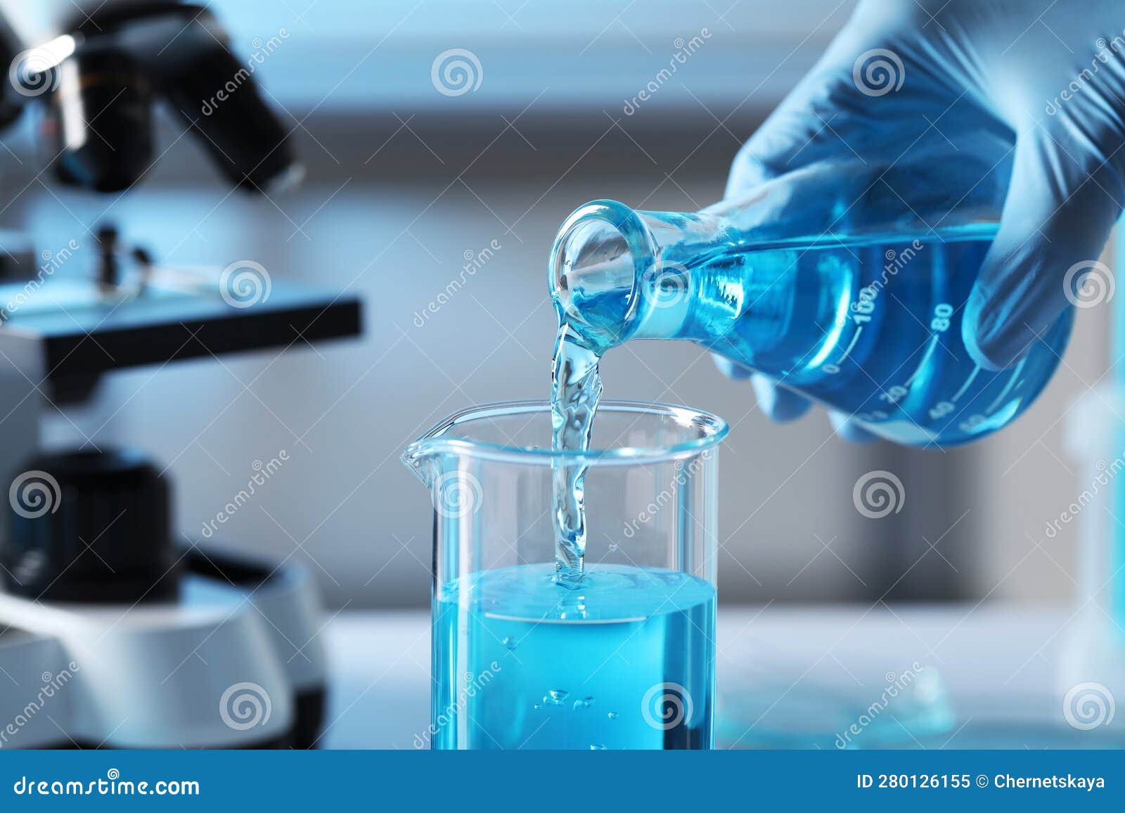 Scientist Pouring Light Blue Liquid from Flask into Beaker in ...