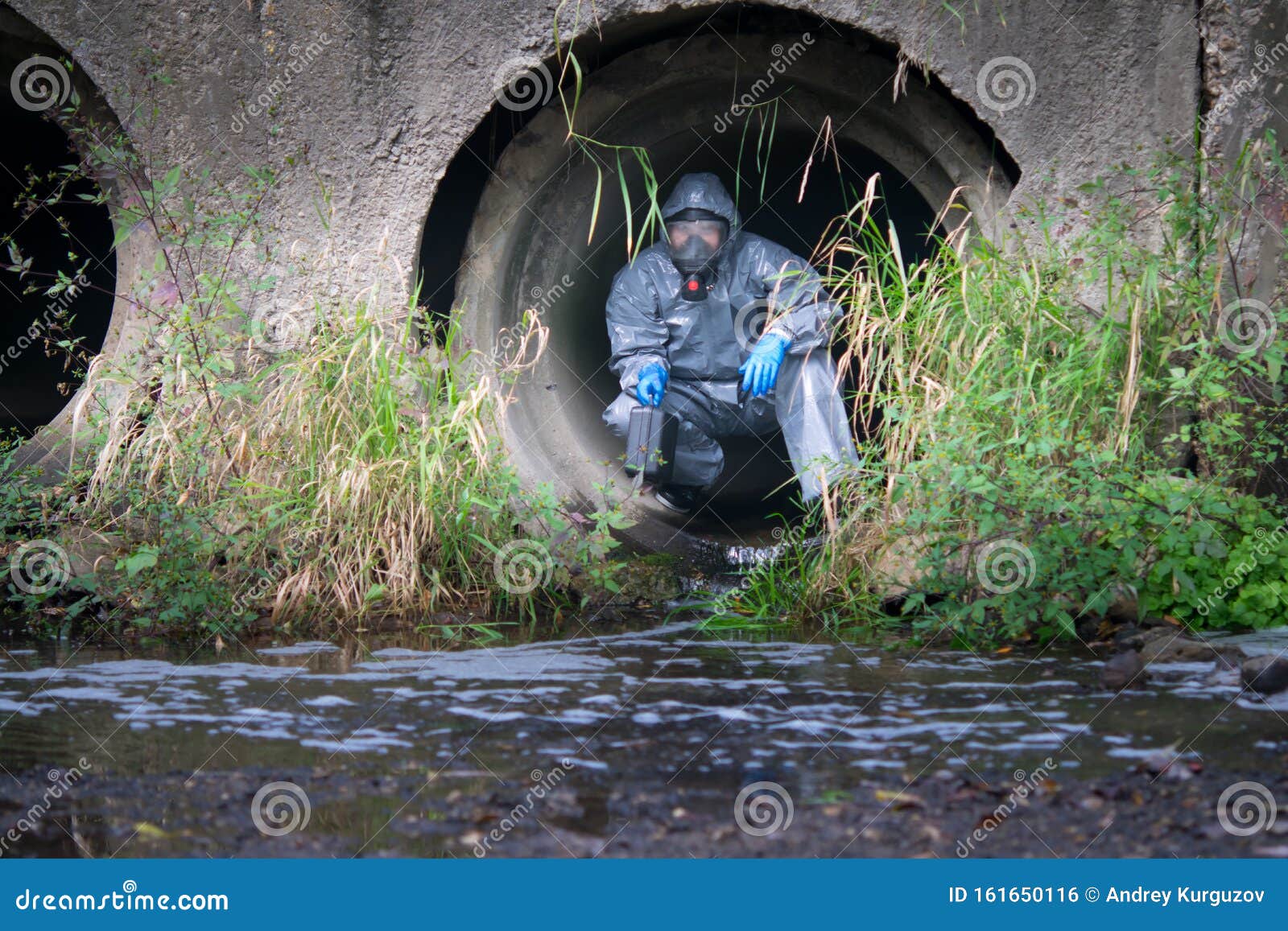 Scientist in Protective Clothing, with a Suitcase Sitting in a Drain ...