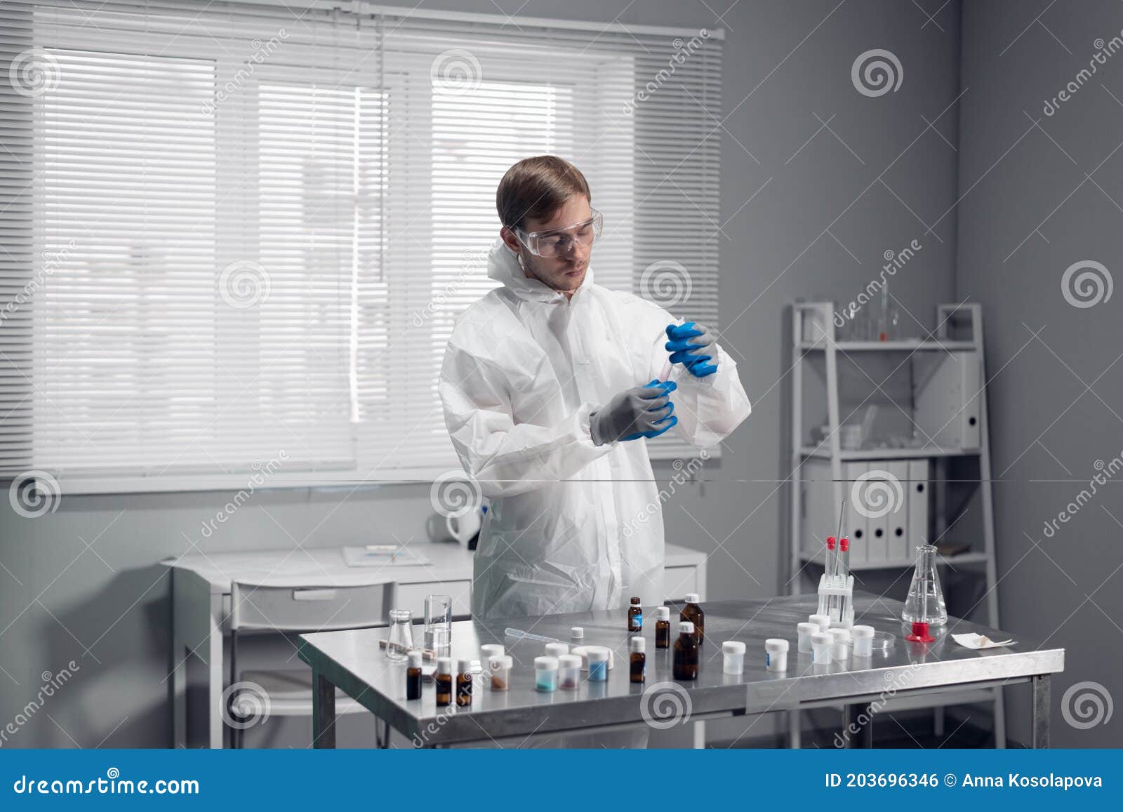A Scientist in Protective Eyewear and White Overalls Standing at the ...