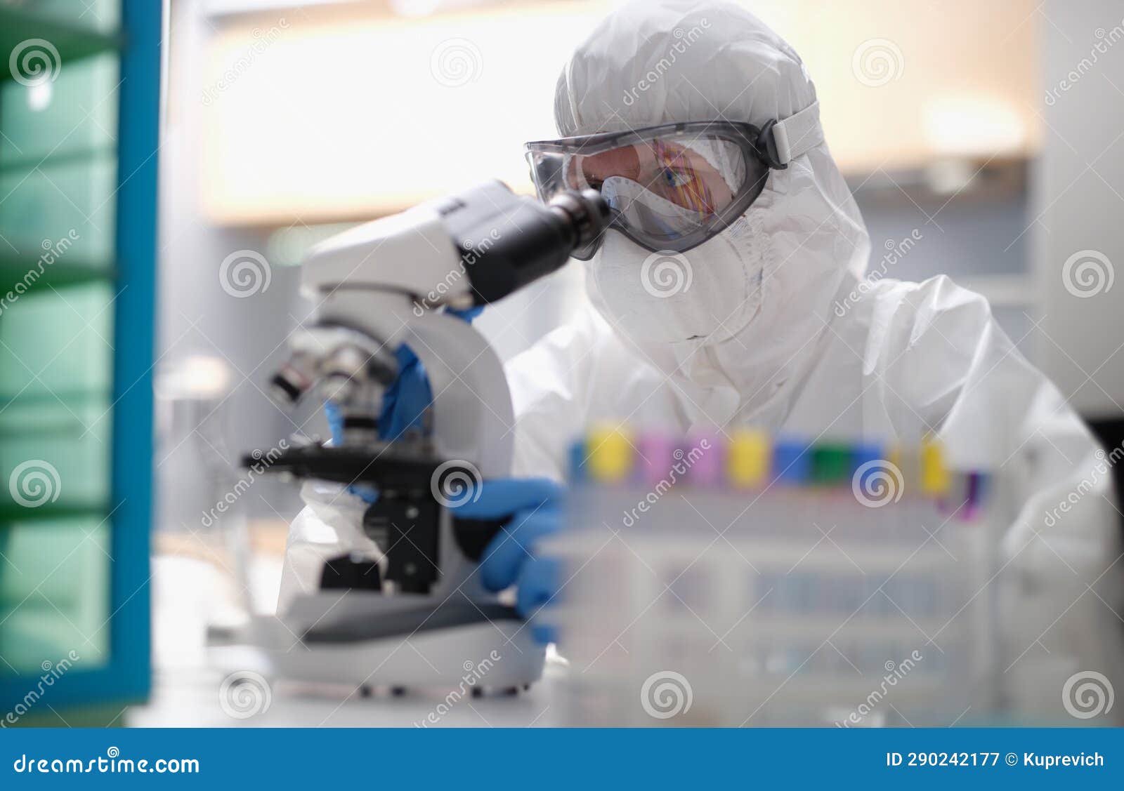Scientist in a Protective Suit Looking through a Microscope in Modern ...