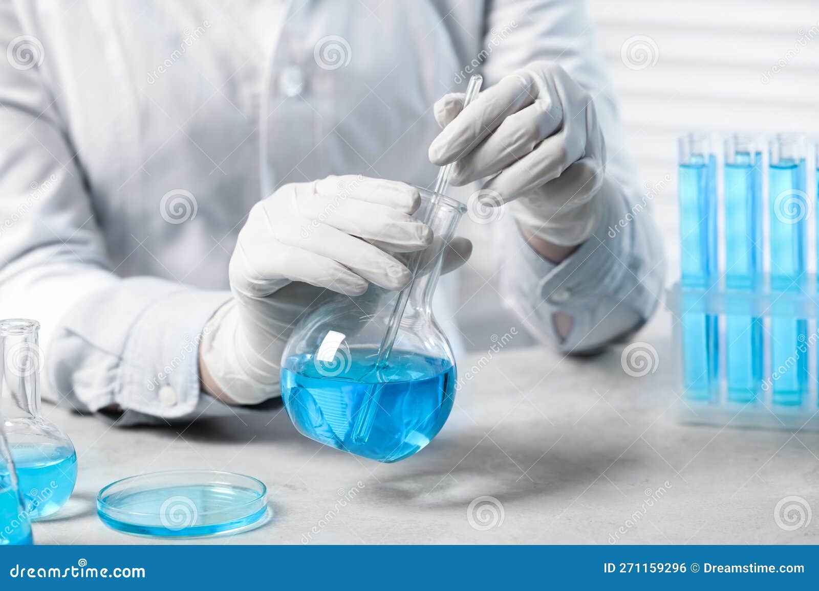 Scientist Taking Sample of Light Blue Liquid at White Table in ...