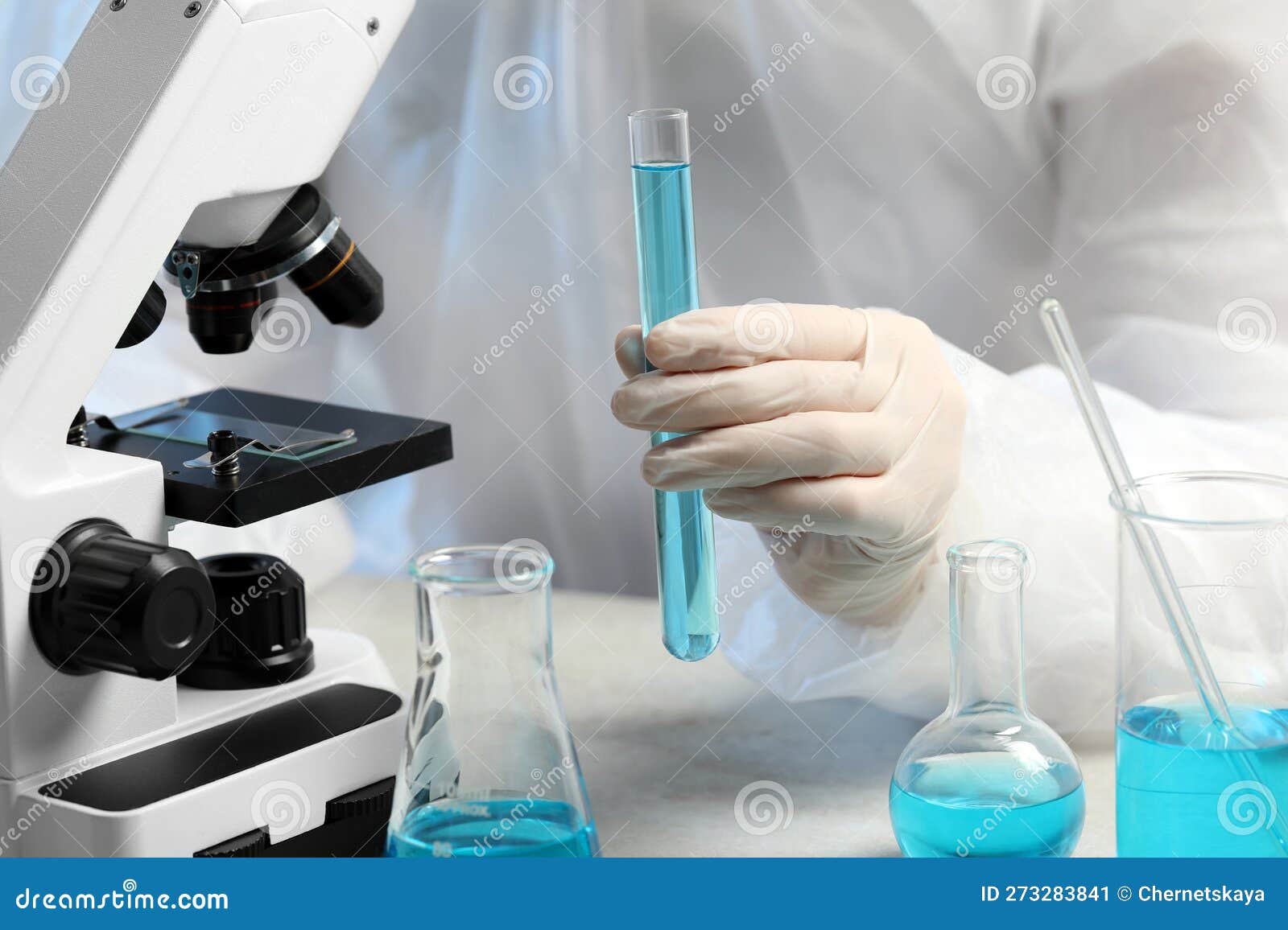Scientist with Test Tube of Light Blue Liquid Near Microscope in ...