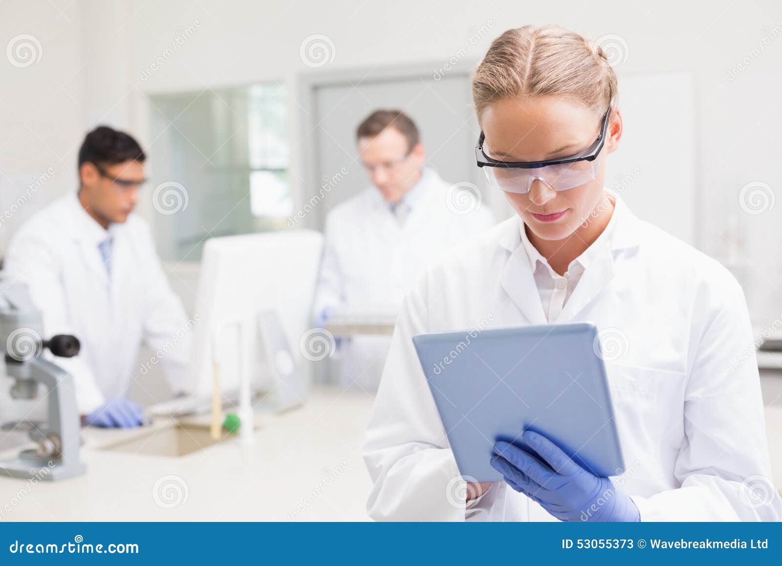 Scientist Using Tablet while Colleagues Working Behind Stock Image ...