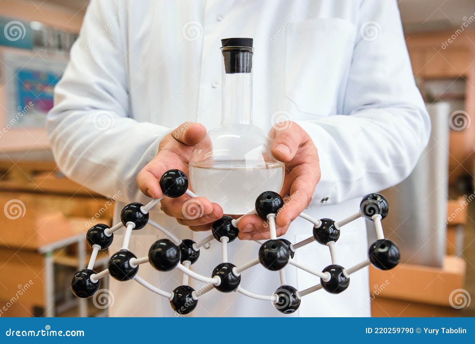 A Scientist, in a White Coat, Holds a Flask and a Model of a Molecule ...