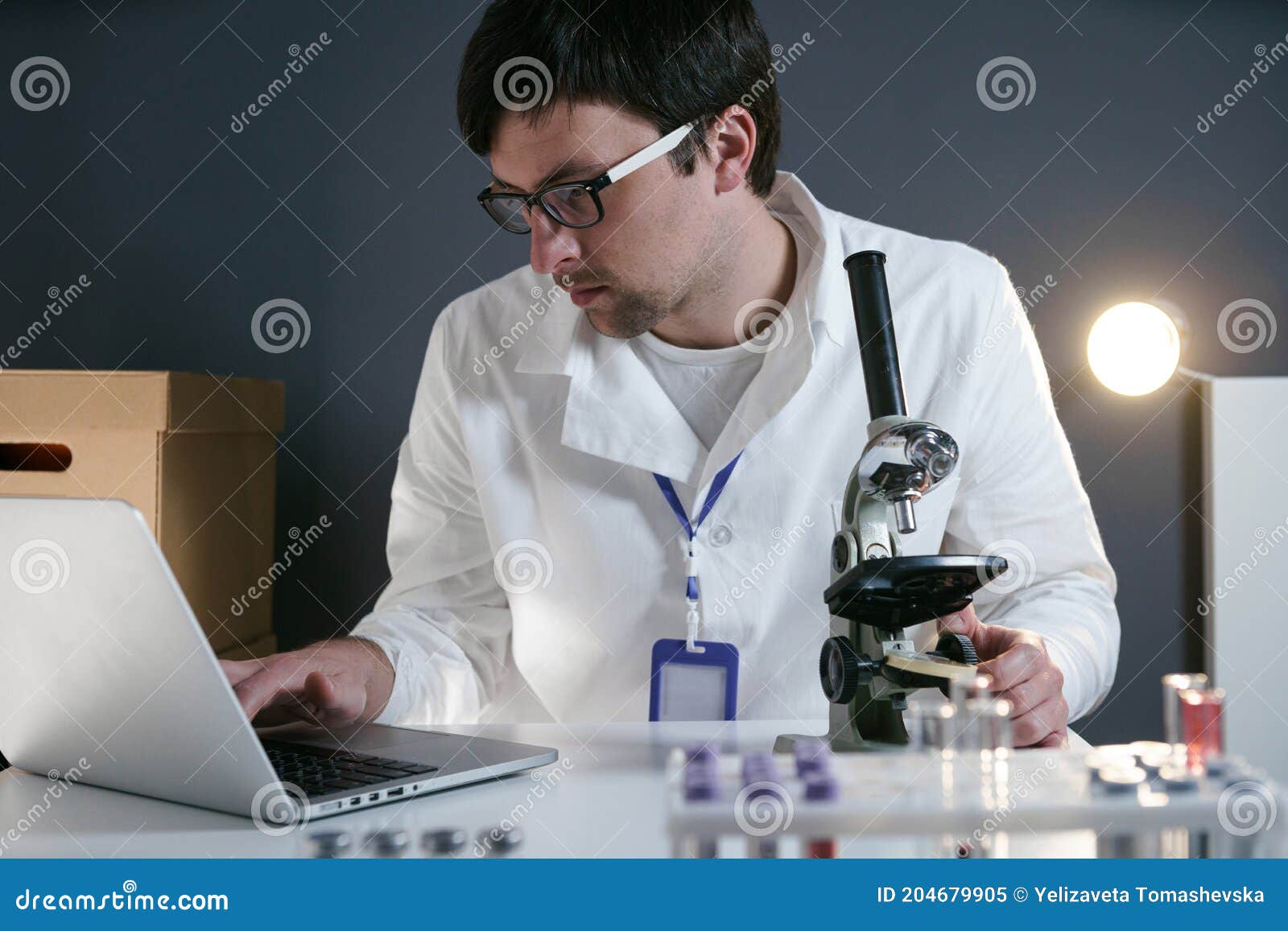 Scientist at Workspace in Laboratory with Microscope, Computer, and ...