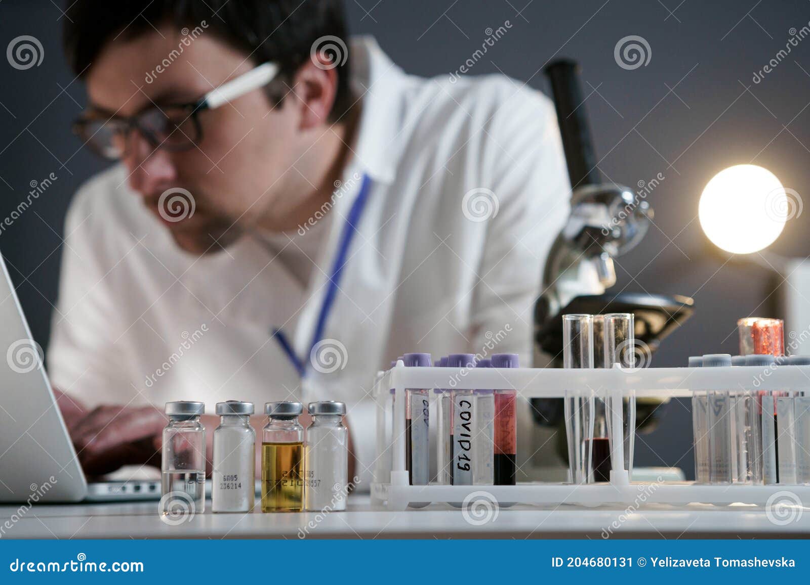Scientist At Workspace In Laboratory With Microscope, Computer, And ...