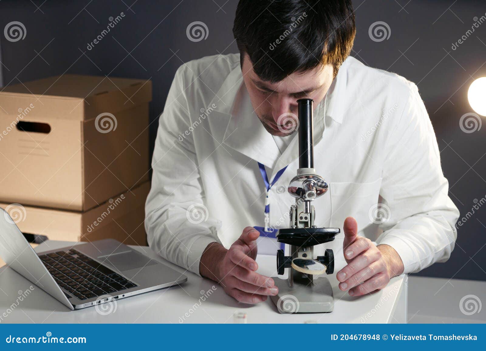 Scientist At Workspace In Laboratory With Microscope, Computer, And ...