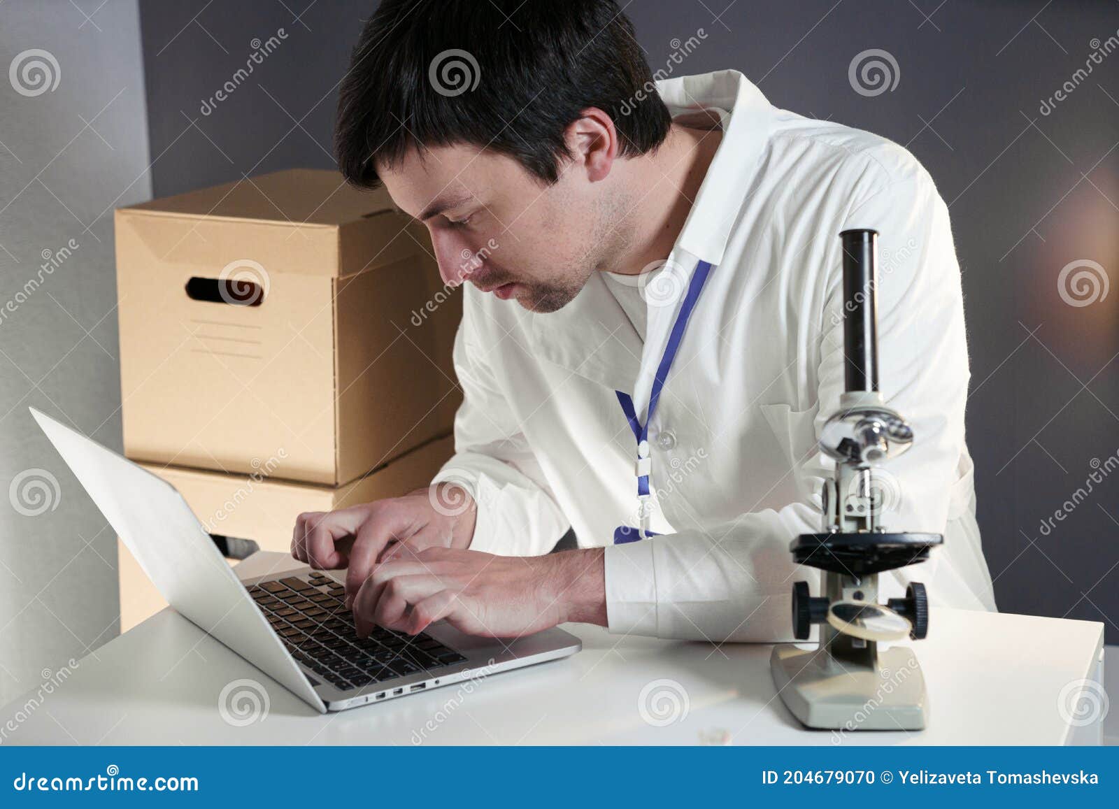 Scientist At Workspace In Laboratory With Microscope, Computer, And ...