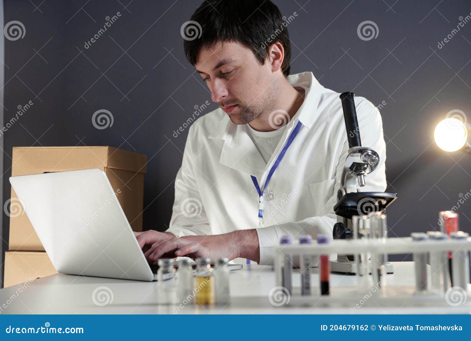 Scientist At Workspace In Laboratory With Microscope, Computer, And ...