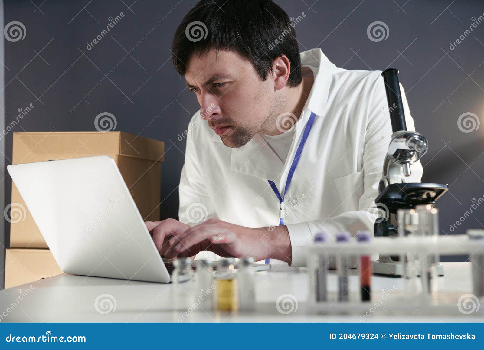 Scientist at Workspace in Laboratory with Microscope, Computer, and ...
