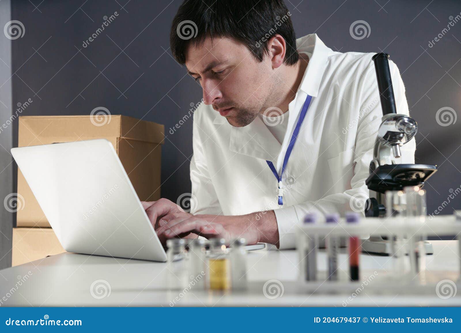 Scientist at Workspace in Laboratory with Microscope, Computer, and ...