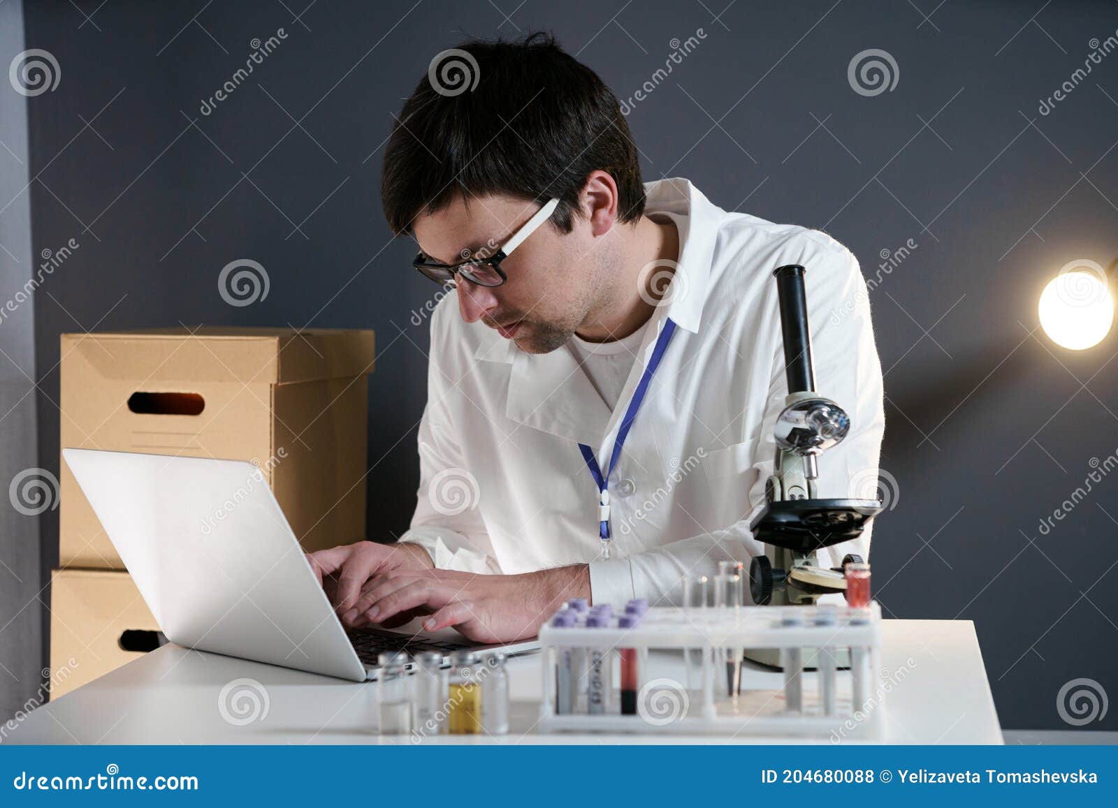 Scientist at Workspace in Laboratory with Microscope, Computer, and ...