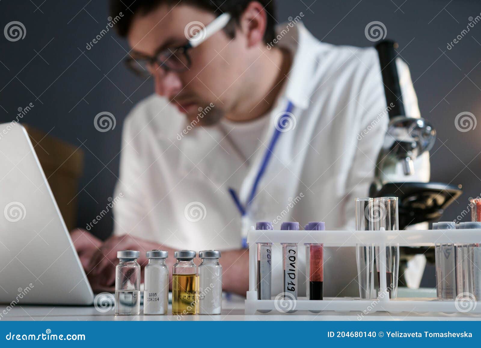 Scientist At Workspace In Laboratory With Microscope, Computer, And ...
