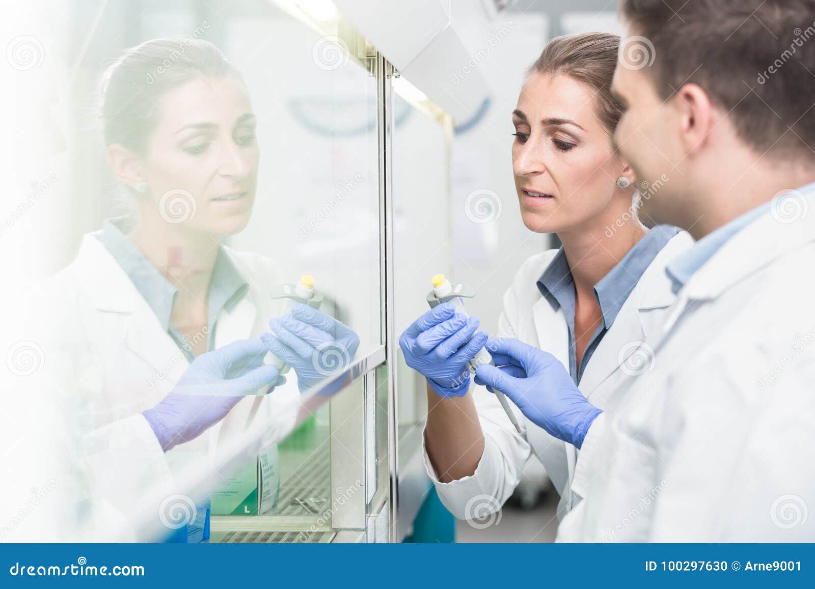 Scientists in Laboratory Preparing Samples Under Splashback Stock Photo ...
