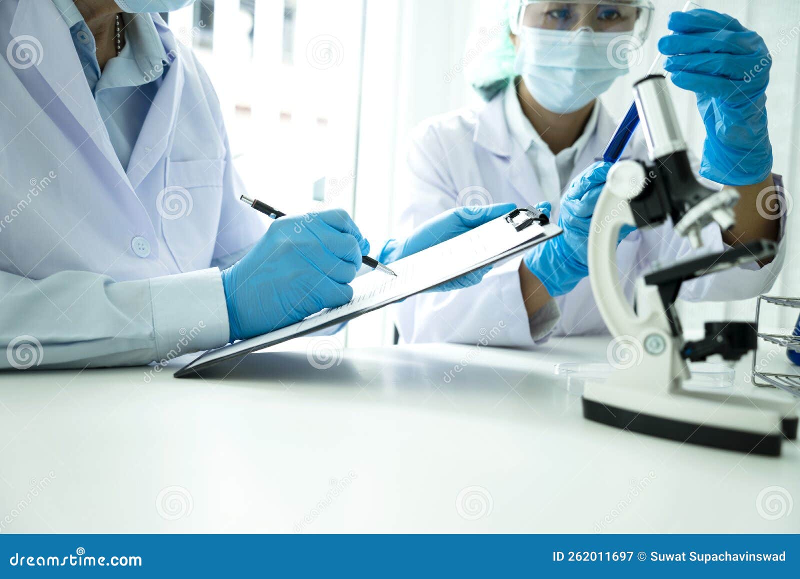 Scientists are Looking at the Microscope and Taking Notes Stock Image ...