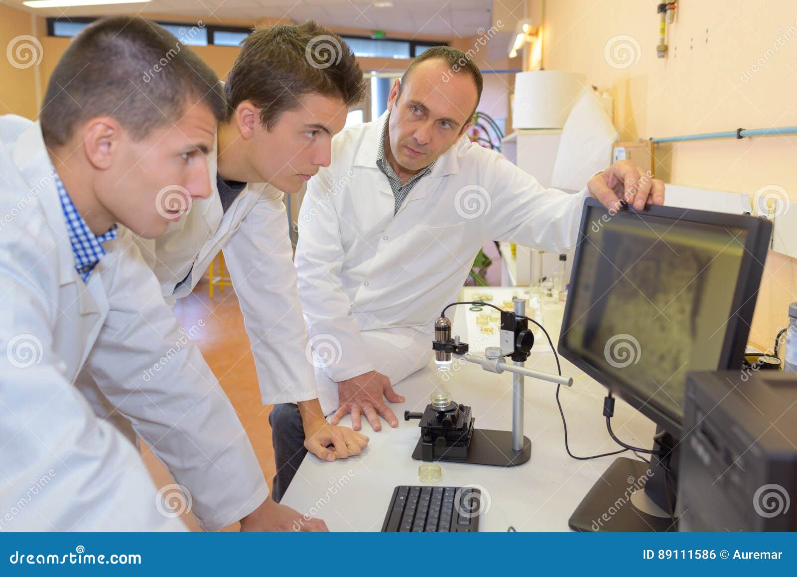 Scientists Looking at Samples on Screen through Microscope Stock Photo ...