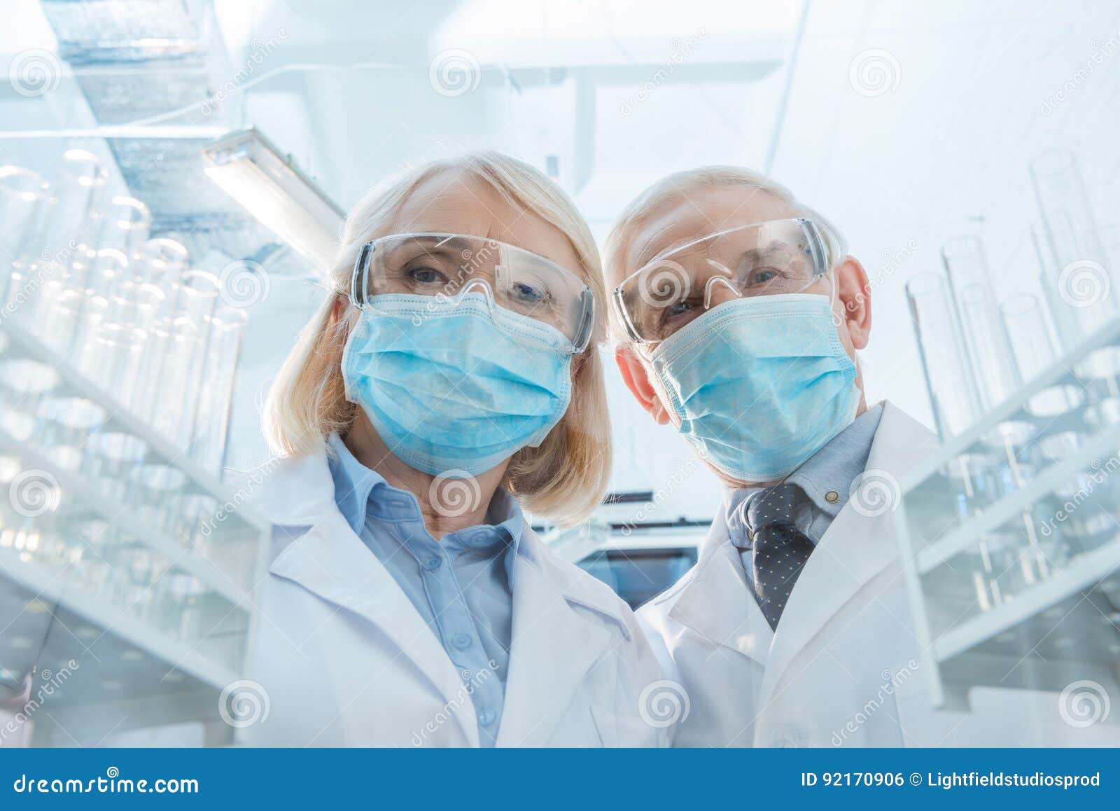 Scientists in Protective Masks and Glasses Standing between Empty Test ...
