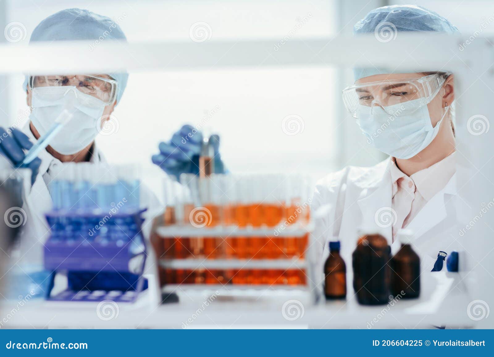 Scientists in Protective Masks Standing in Front of a Rack of Test ...