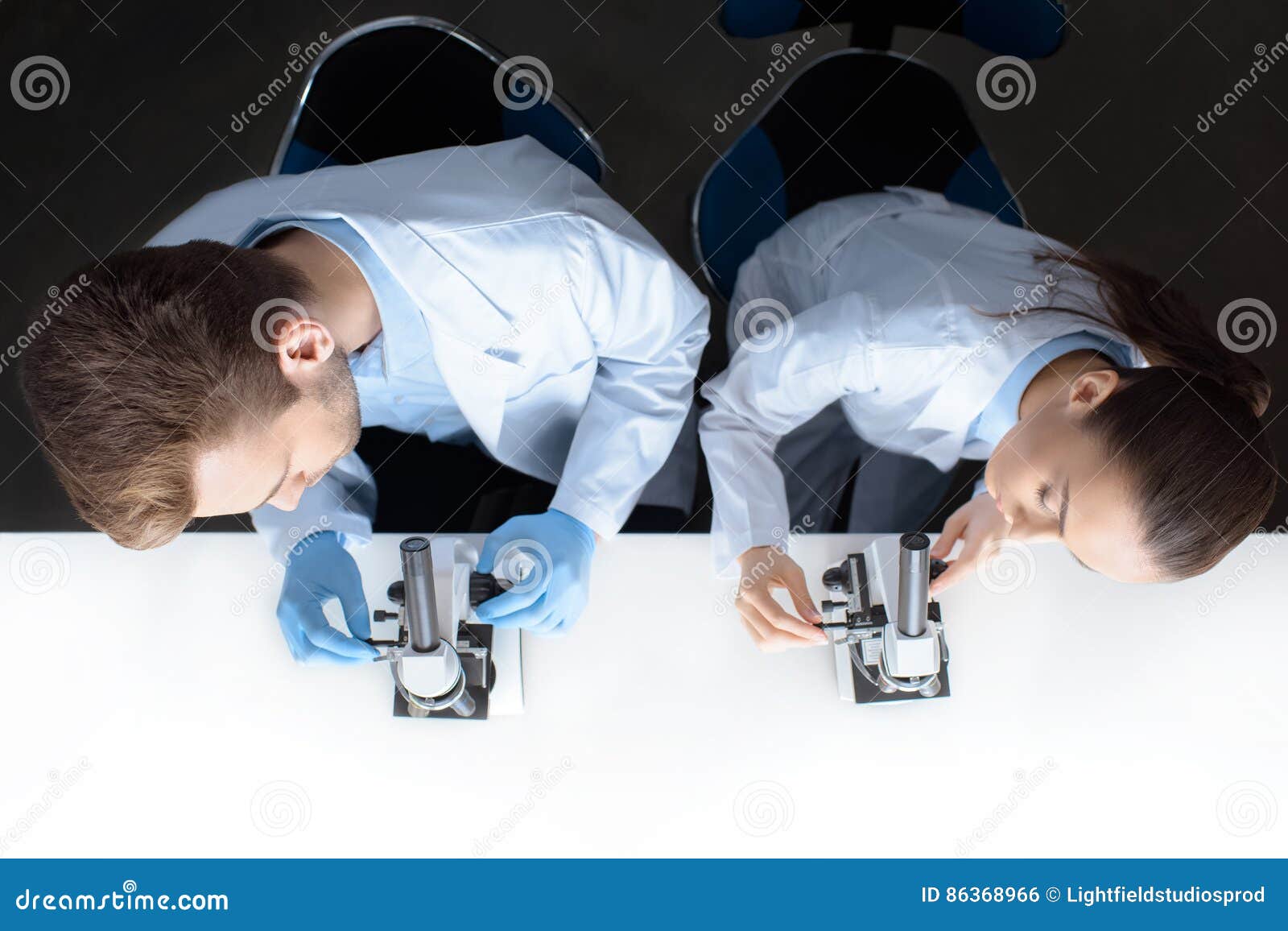 Scientists in Uniforms Working with Microscopes in Laboratory Stock ...