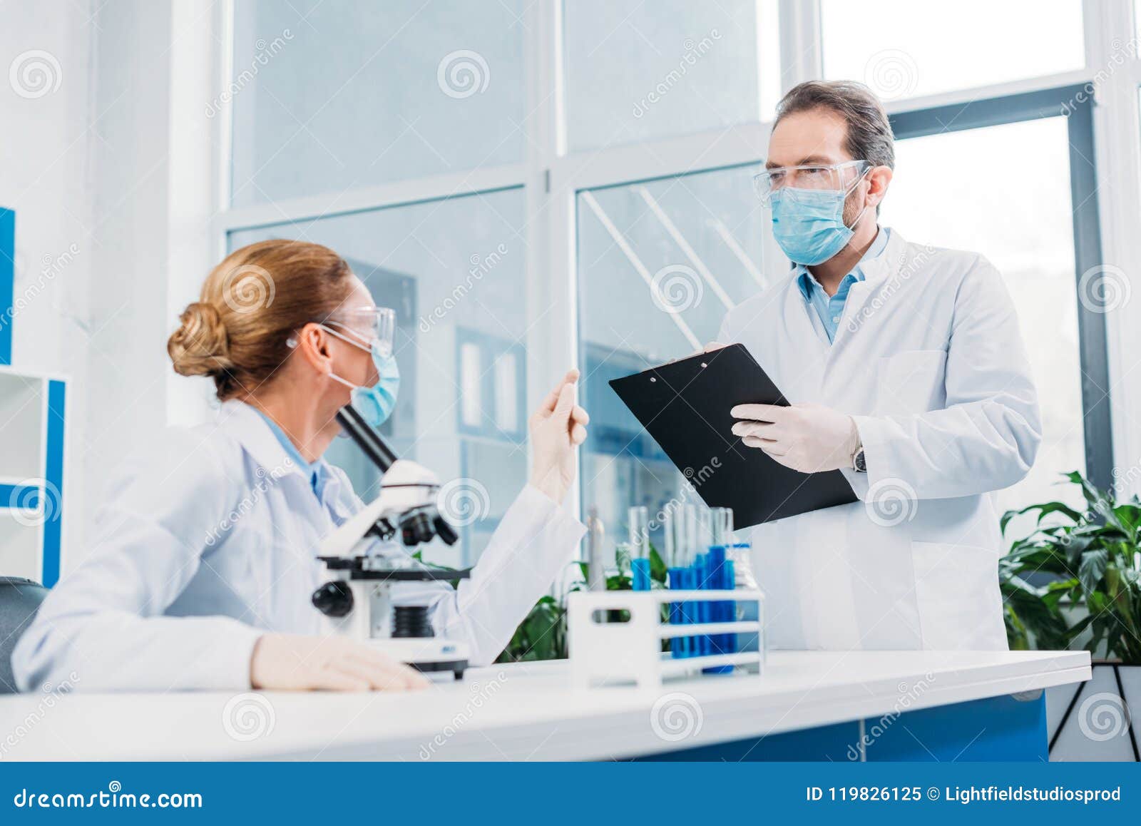 Scientists in White Coats and Goggles Working with Reagents and ...
