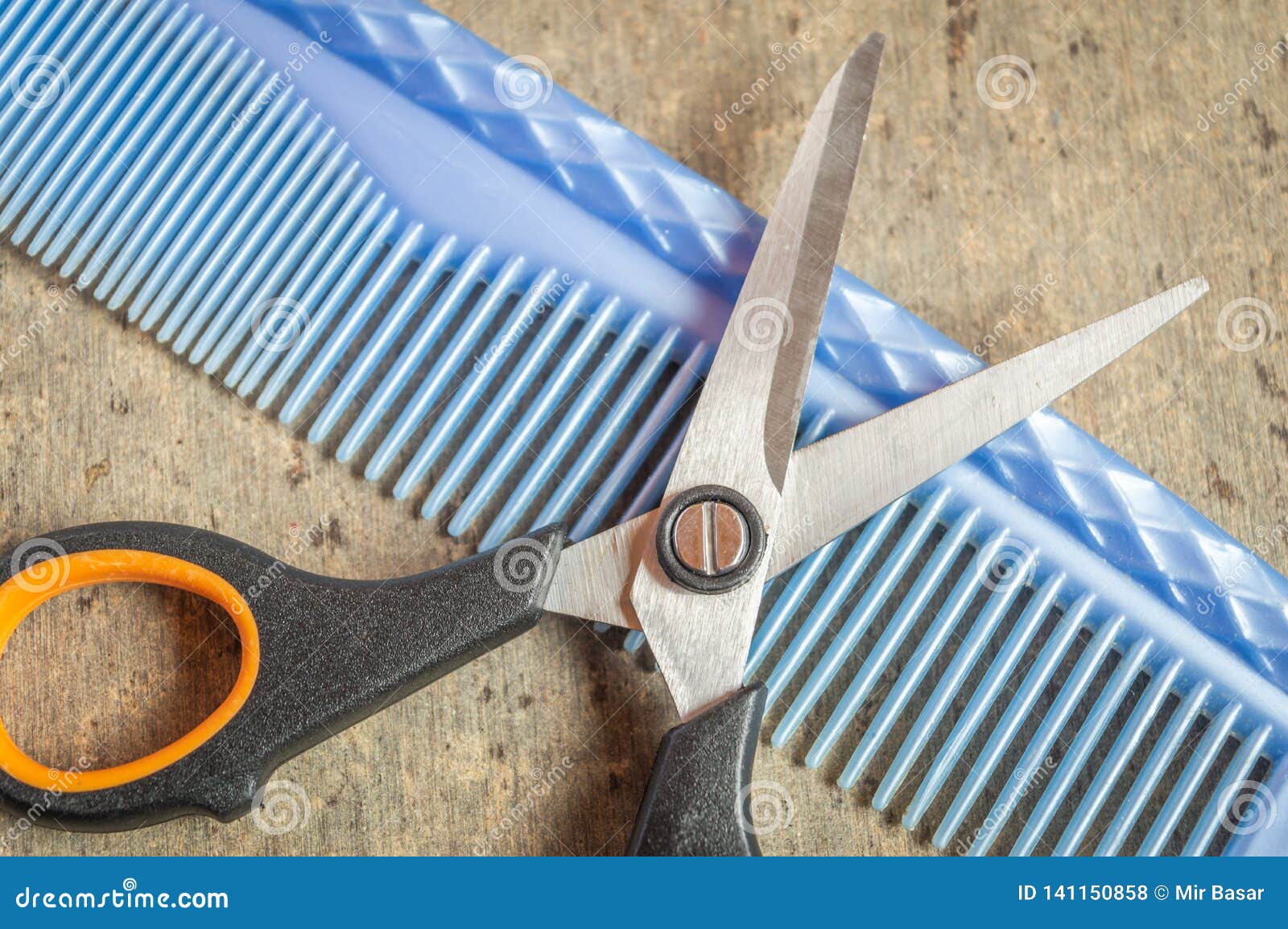 A Scissors and a Blue Comb Kept on a Grey Wooden Textured Table Top ...
