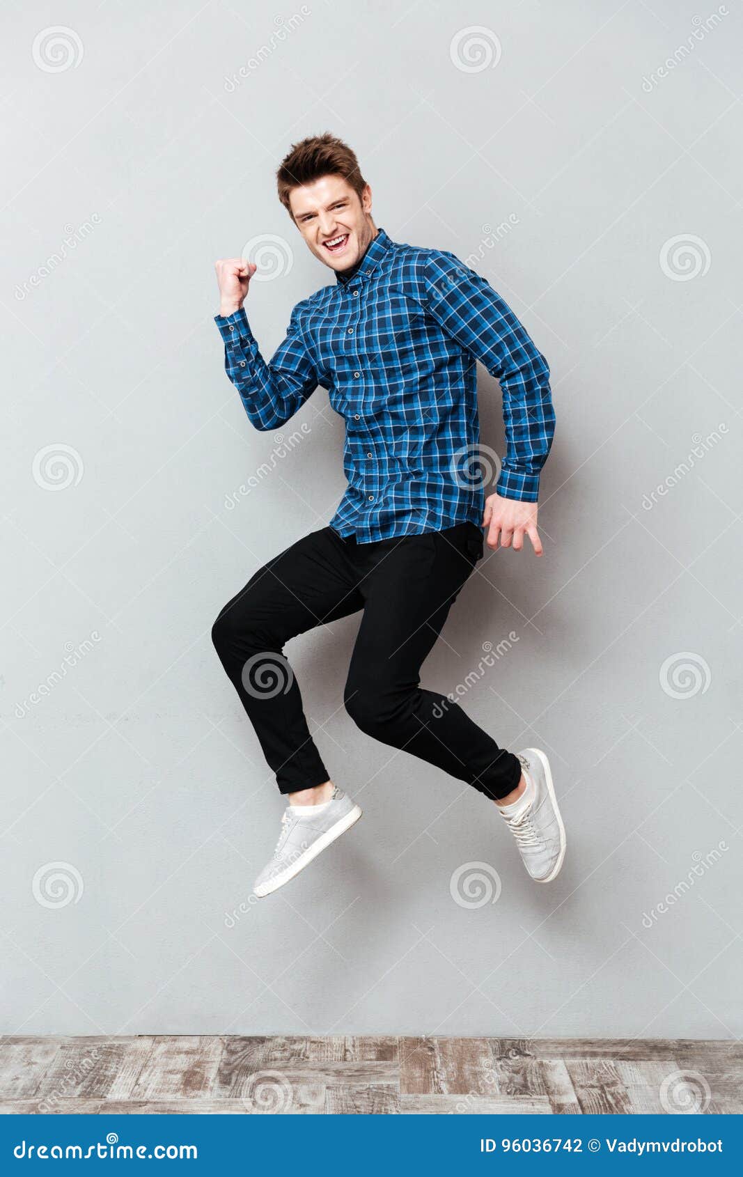 Screaming Young Man Standing Over Grey Wall and Jumping. Stock Photo ...