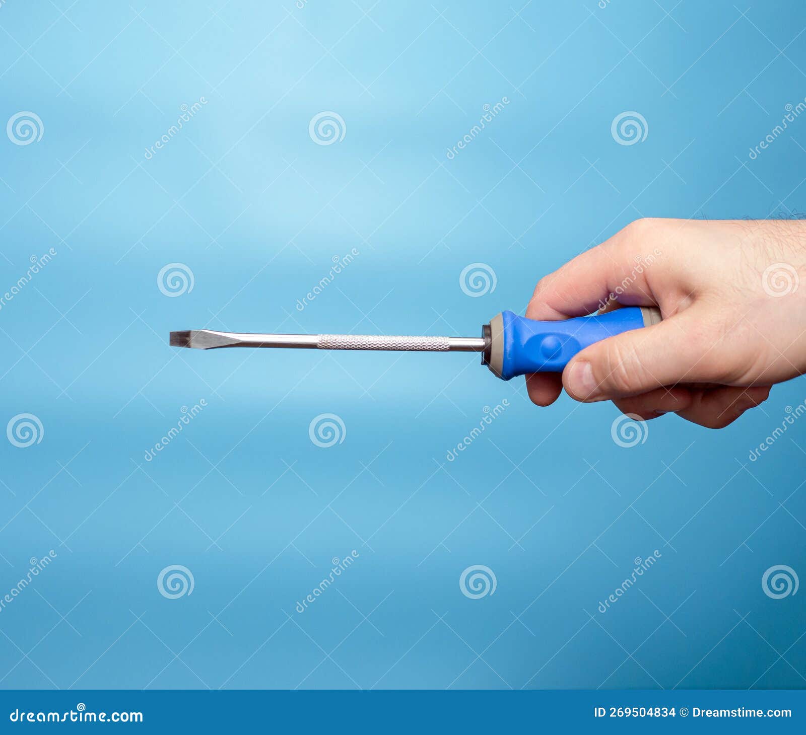 Screwdriver in a Man S Hand on a Blue Background. Construction or ...