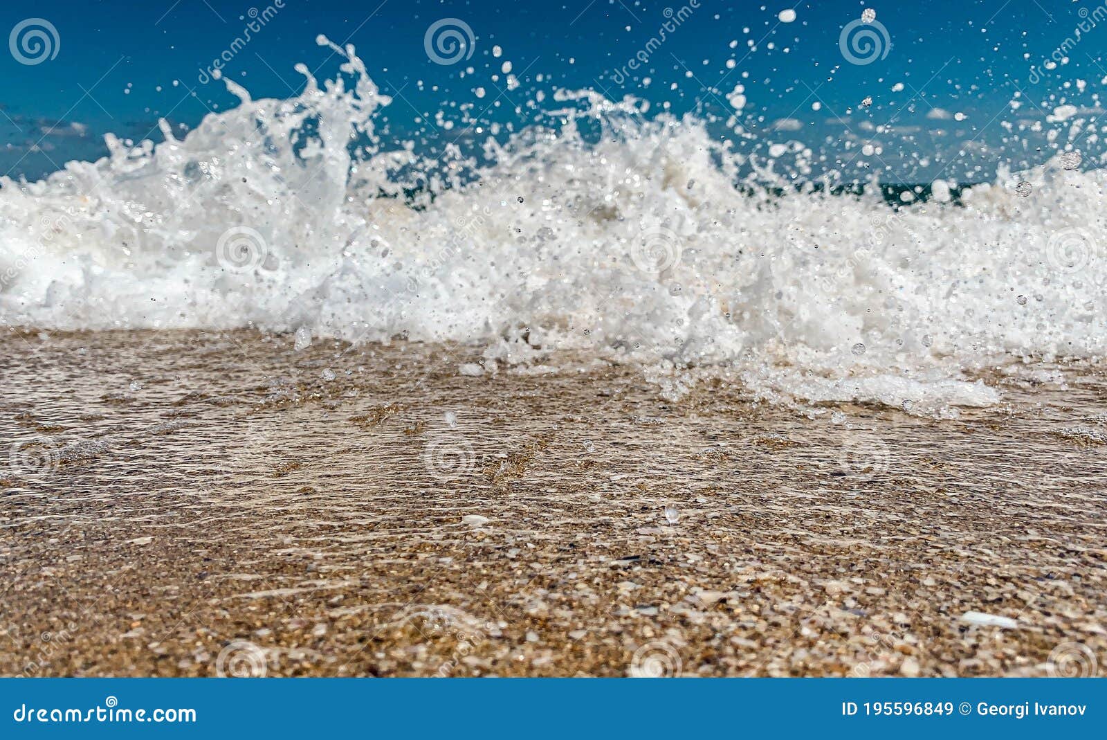 Sea Wave Crashing The Sandy Beach Shore Spraying Water Drops Stock