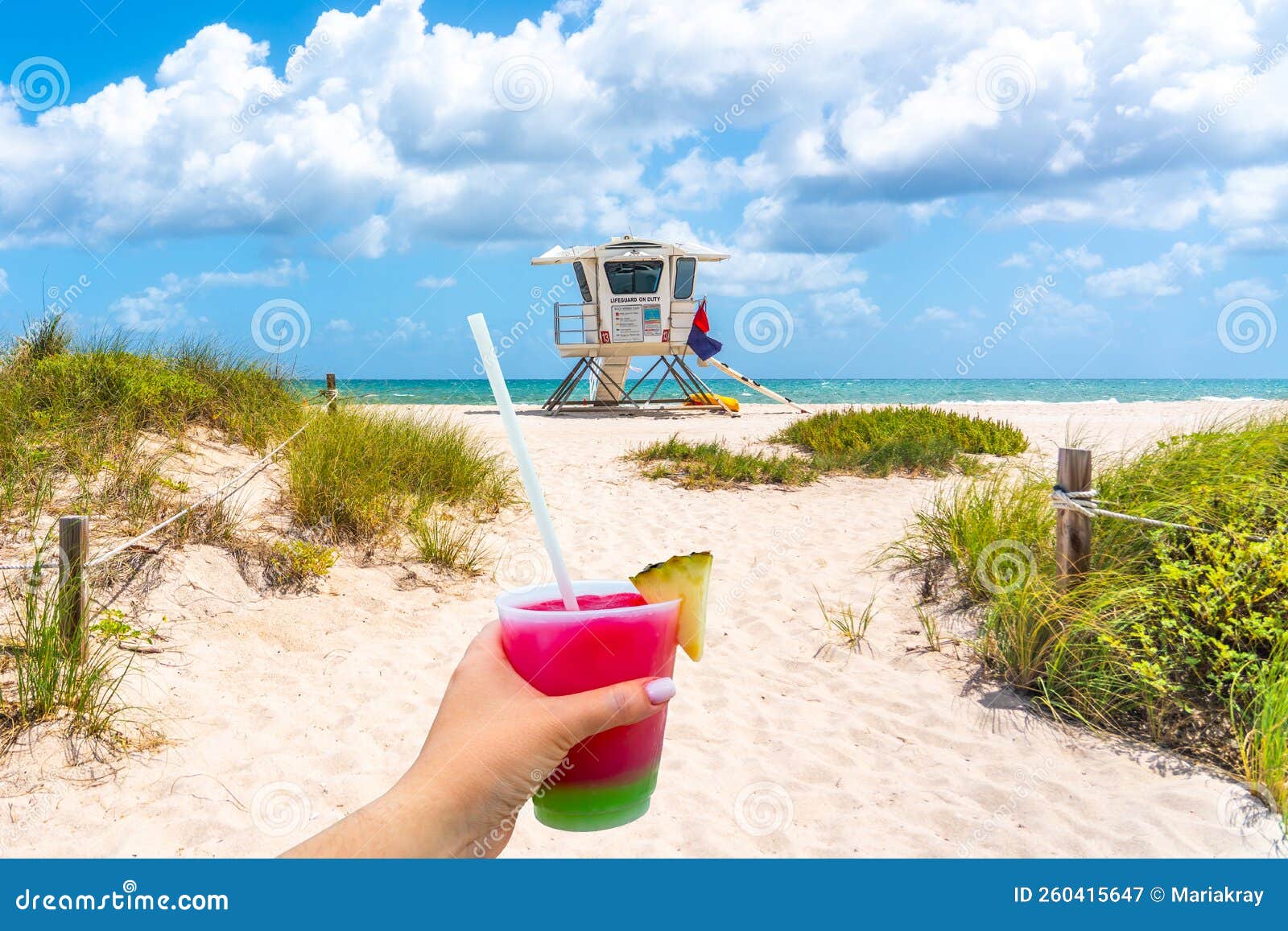Seafront Beach Promenade With Hand Holding Cocktail On Sunny Day In