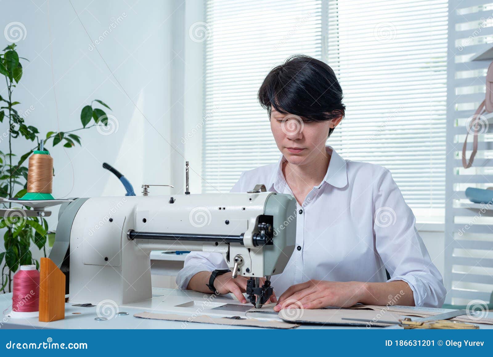 Seamstress Girl is at the Workplace Behind the Sewing Machine Stock ...