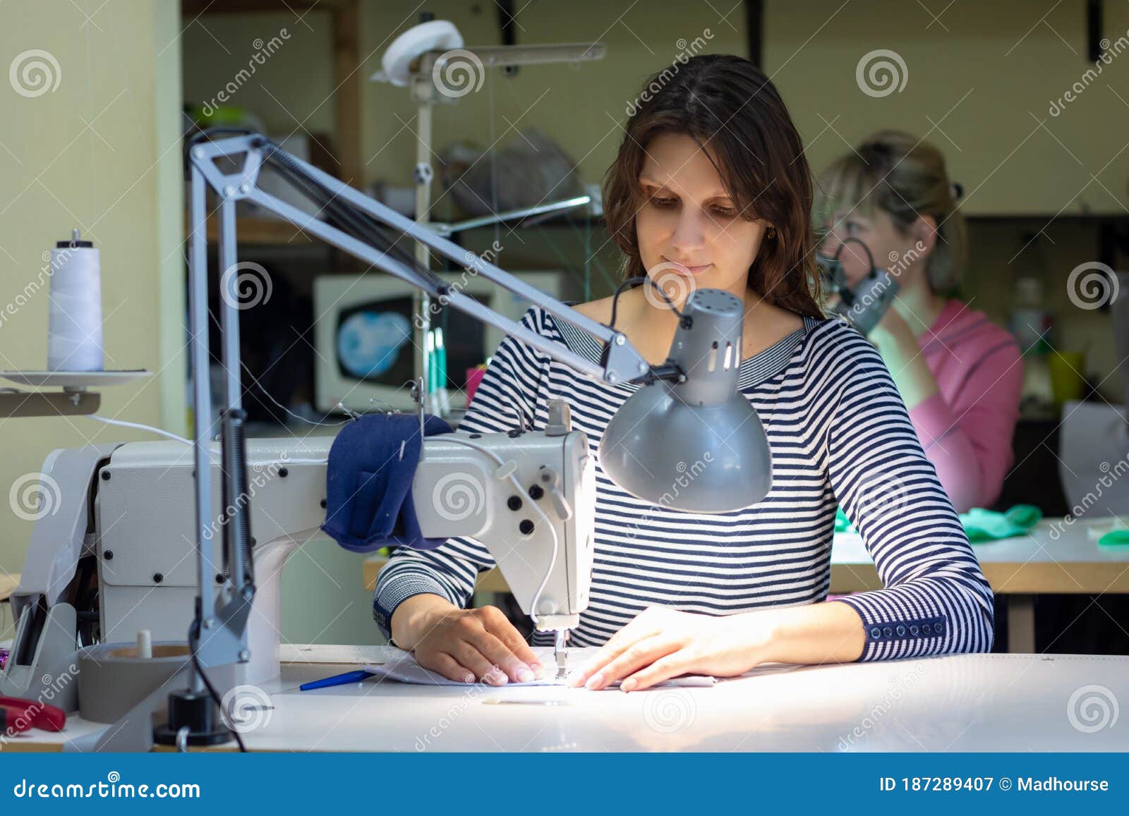 A Seamstress Works Behind a Sewing Machine in a Sewing Shop at Her ...